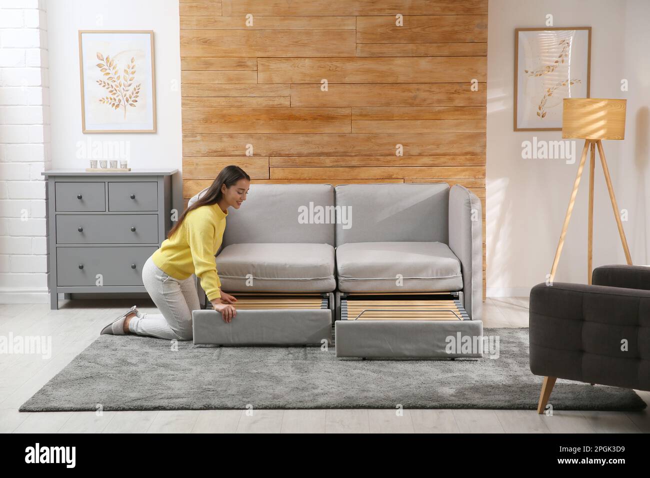 Young woman unfolding sofa into a bed in room. Modern interior Stock ...