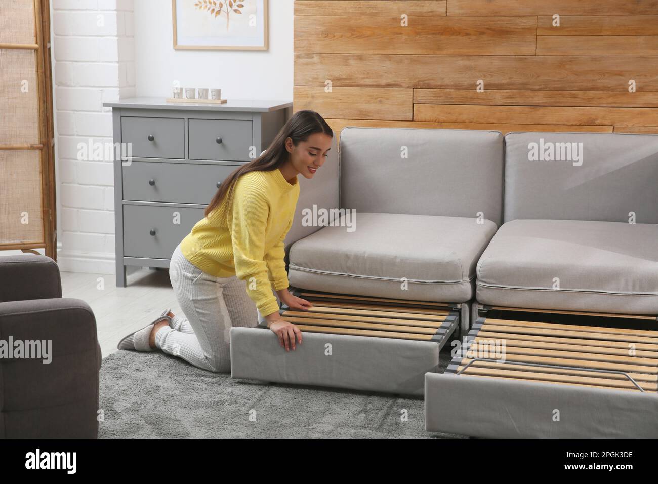 Young woman unfolding sofa into a bed in room. Modern interior Stock ...