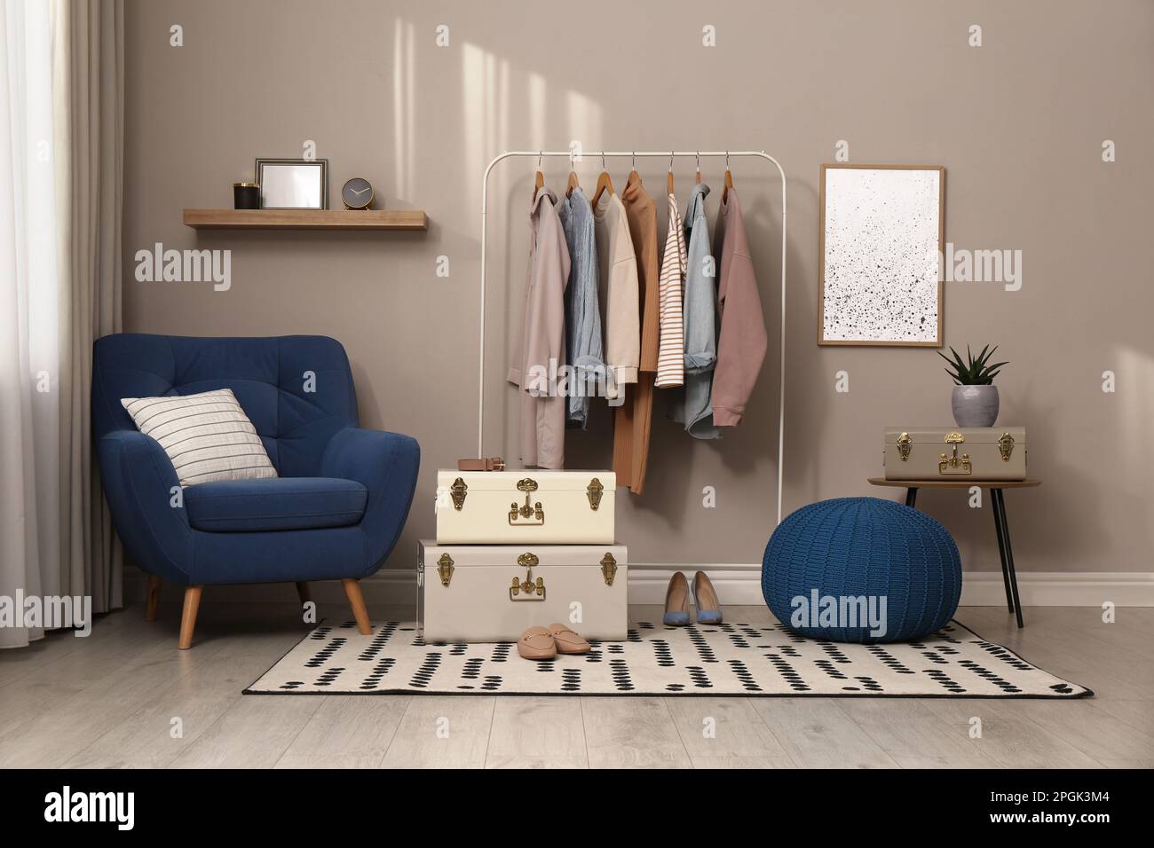Stylish room interior with comfortable armchair, clothes and storage ...