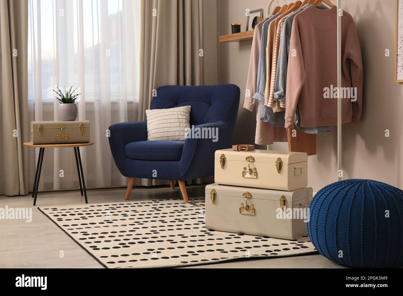 Stylish room interior with comfortable armchair, clothes and storage ...