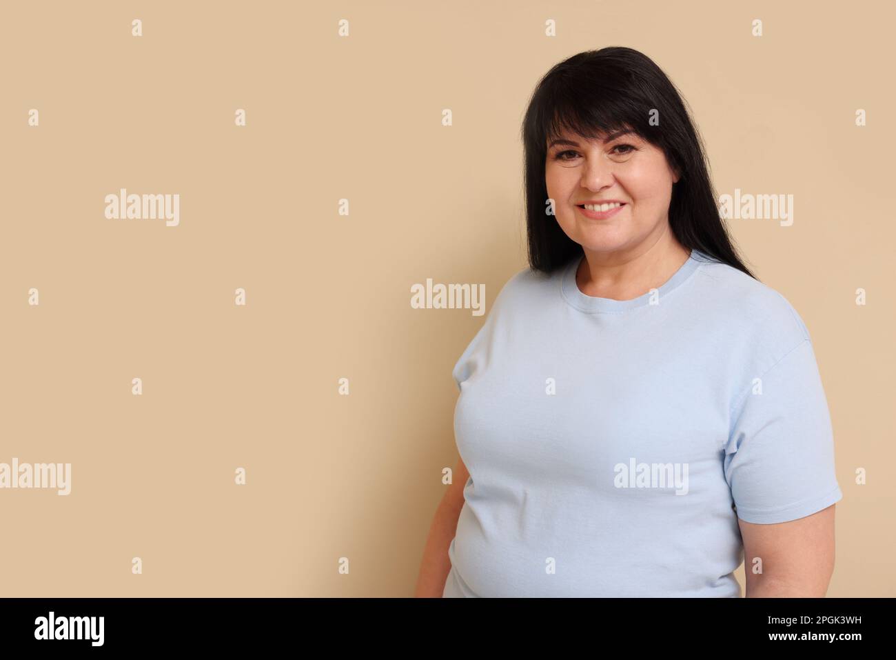 Beautiful overweight mature woman with charming smile on beige ...