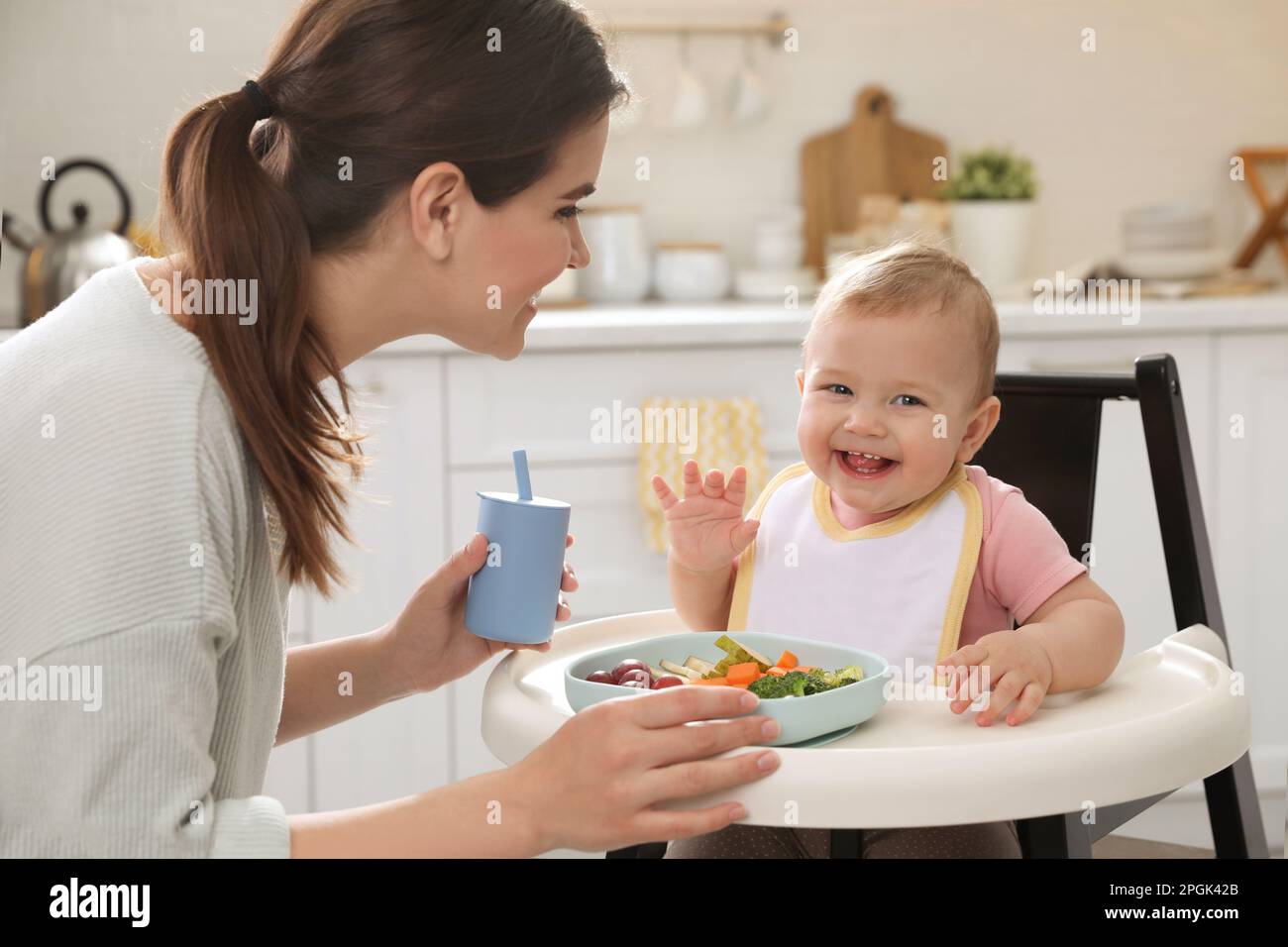 Mother feeding her cute little baby in kitchen Stock Photo - Alamy