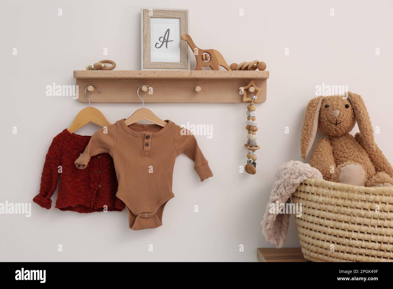 Wooden shelf with baby clothes, toys and accessories in room. Interior ...