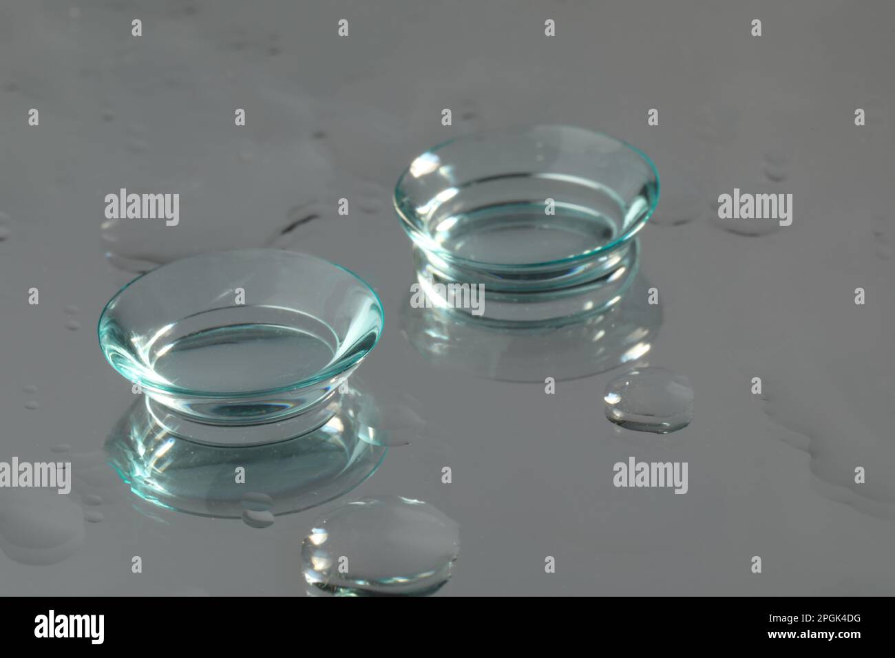 Pair of contact lenses on wet grey reflective surface Stock Photo - Alamy