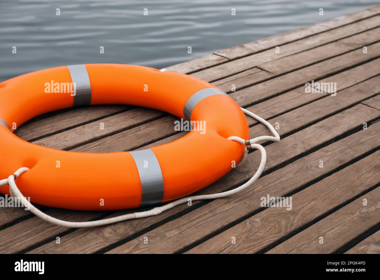 Orange lifebuoy on wooden pier near water. Rescue equipment Stock Photo ...