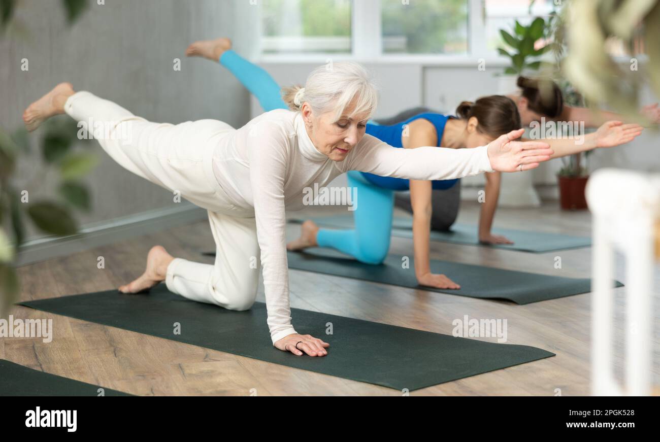 Senior woman standing in balancing asana Dandayamna Bharmanasana Stock ...