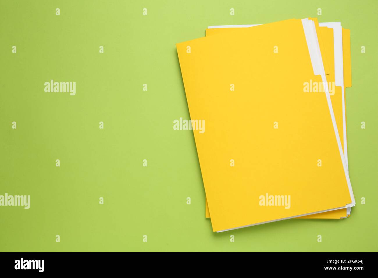 Yellow files with documents on light green background, top view. Space ...