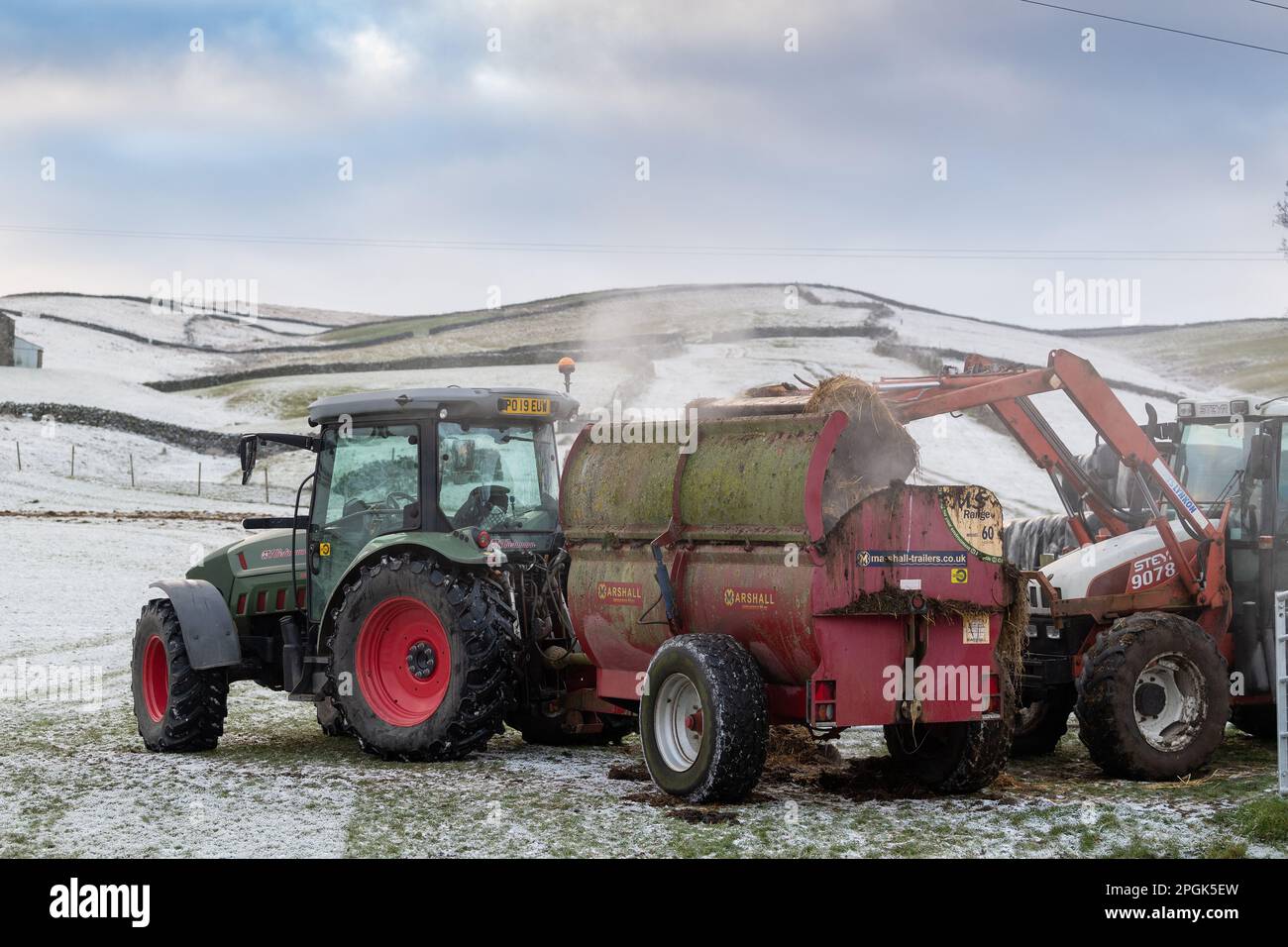 Filling a rotary muck spreader with farm yard manure to spread on ...