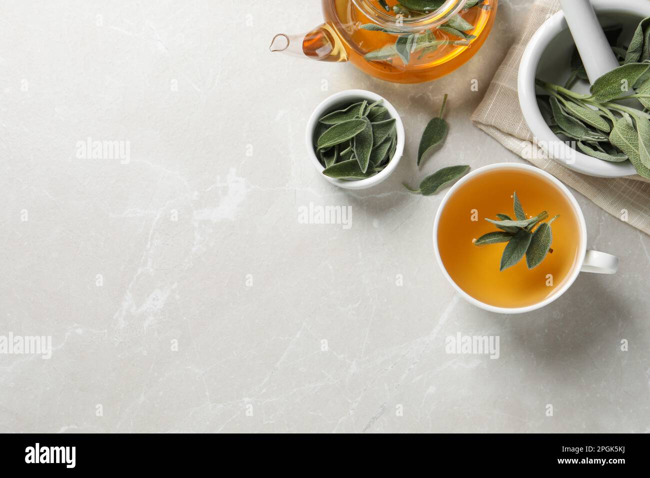 Sage tea and green leaves on light grey marble table, flat lay. Space ...