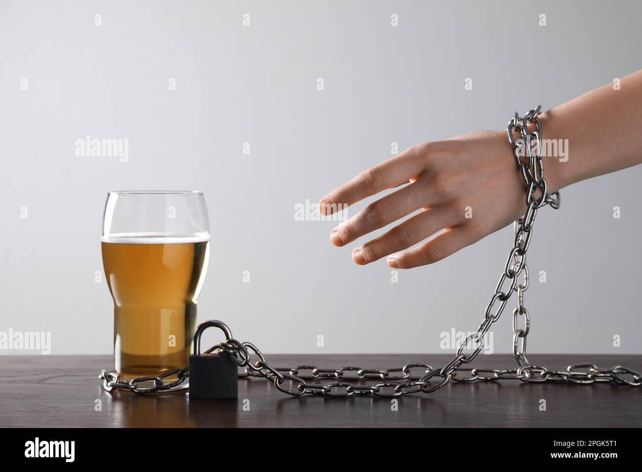 Woman chained to glass of beer at table against white background ...
