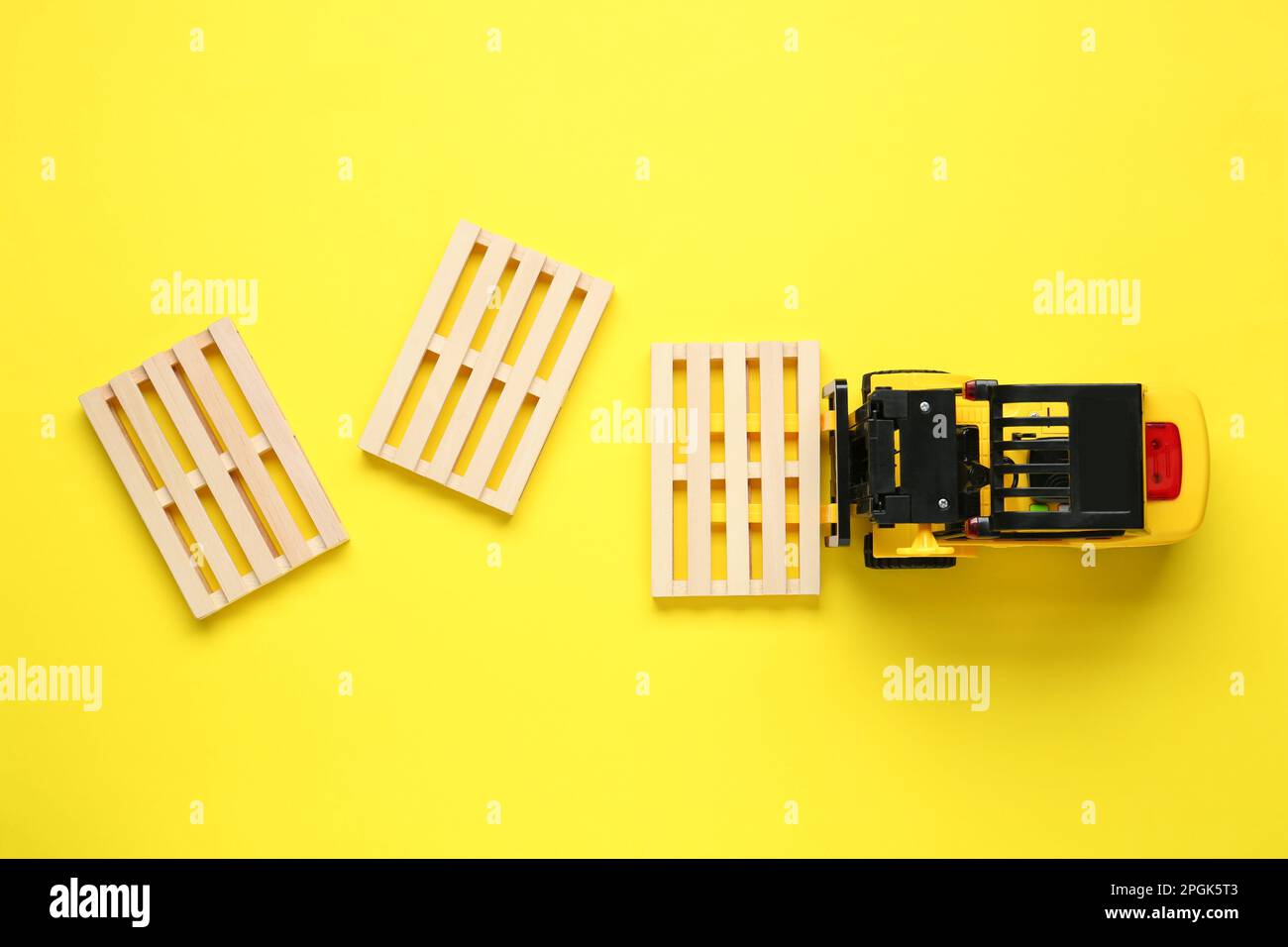 Toy forklift and wooden pallets on yellow background, flat lay Stock ...