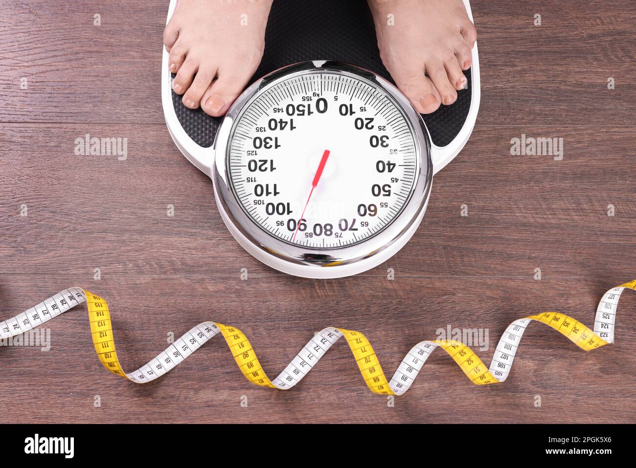 Closeup of woman using scales on floor near measuring tape, top view ...