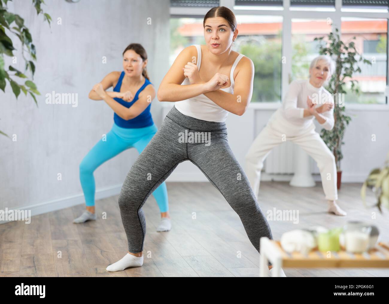 Group of active women practicing energetic dance in modern dance studio ...
