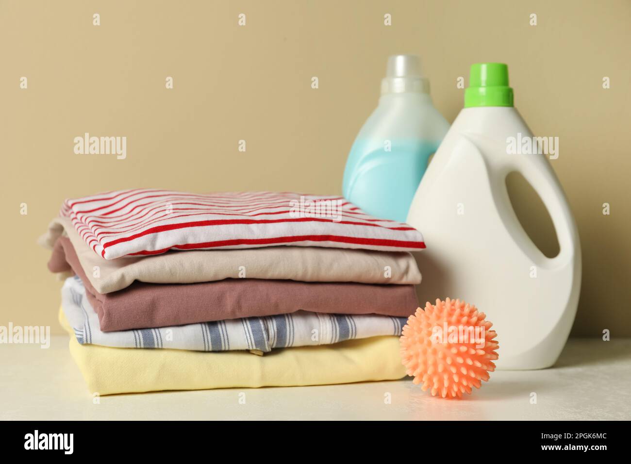 Orange dryer ball, laundry detergents and stacked clean clothes on ...