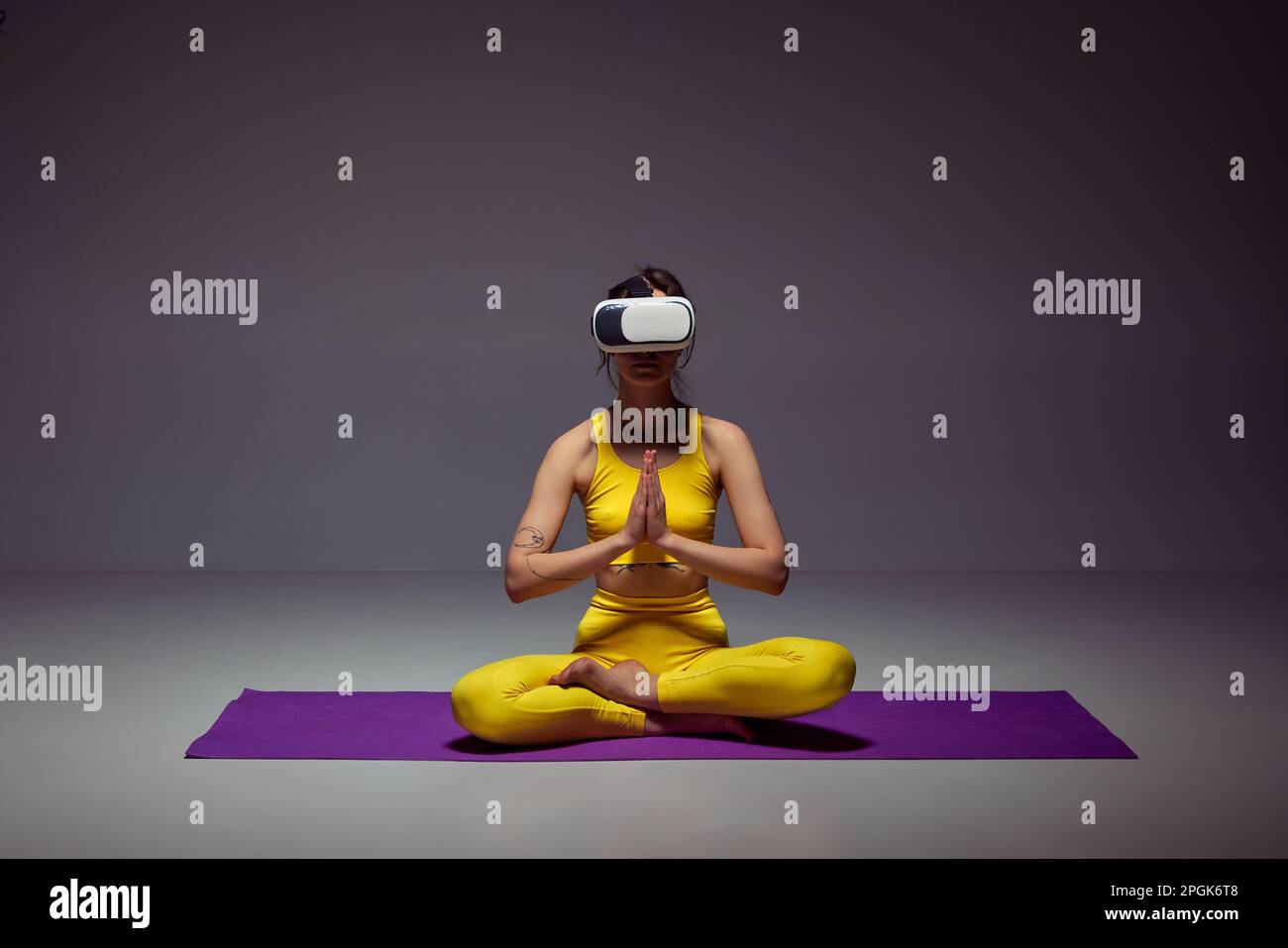 Young slim girl in yellow sportswear training, doing yoga exercises in ...