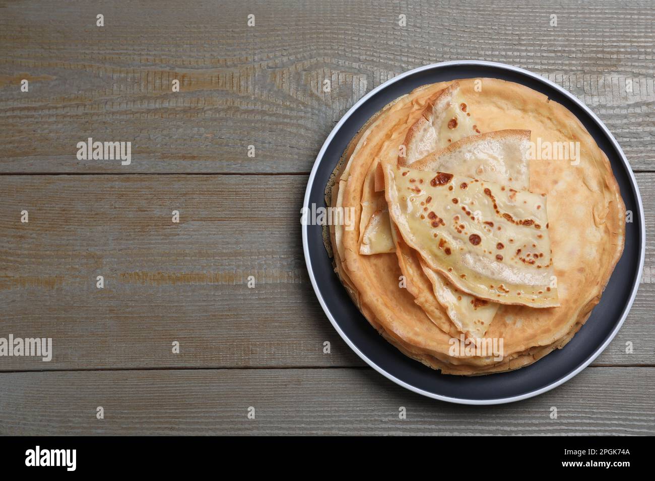 Stack of delicious crepes on grey wooden table, top view. Space for ...
