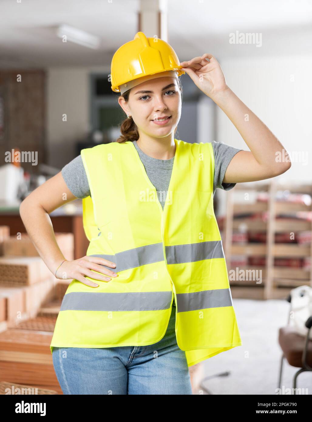 Confident female builder in yellow vest and hard hat at construction ...