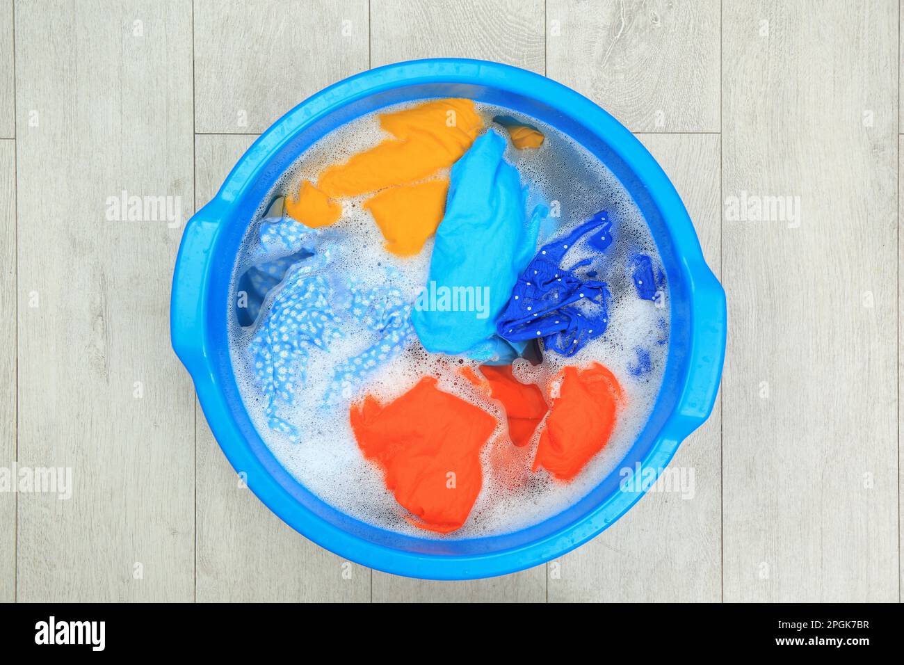 Basin with colorful clothes on floor, top view. Hand washing laundry ...