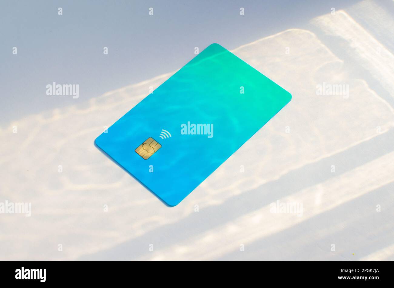 A closeup of a gradient blue and green credit card isolated on an empty ...