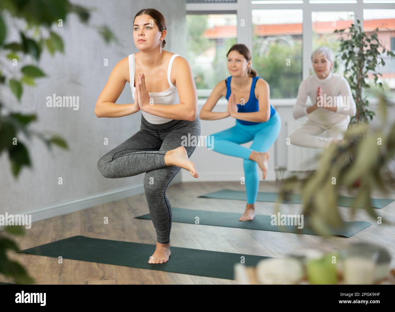 Focused fit women in activewear balancing in Tree posture or Vrksasana ...