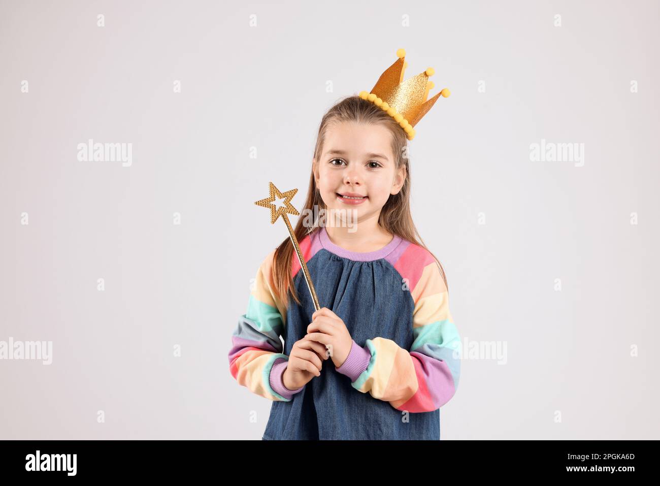 Cute girl in golden crown with magic wand on light grey background ...