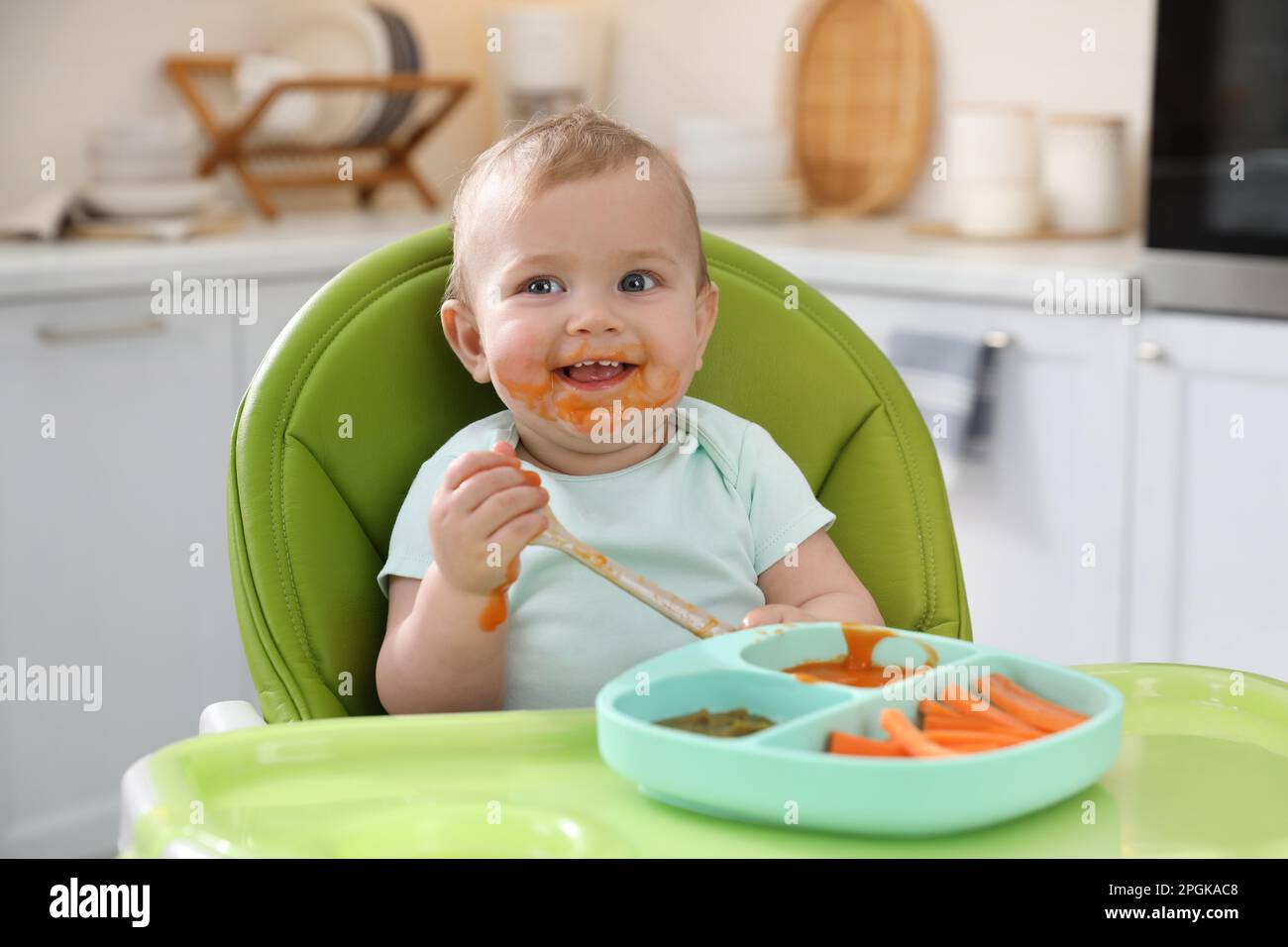 Cute little baby eating food in high chair at kitchen Stock Photo - Alamy