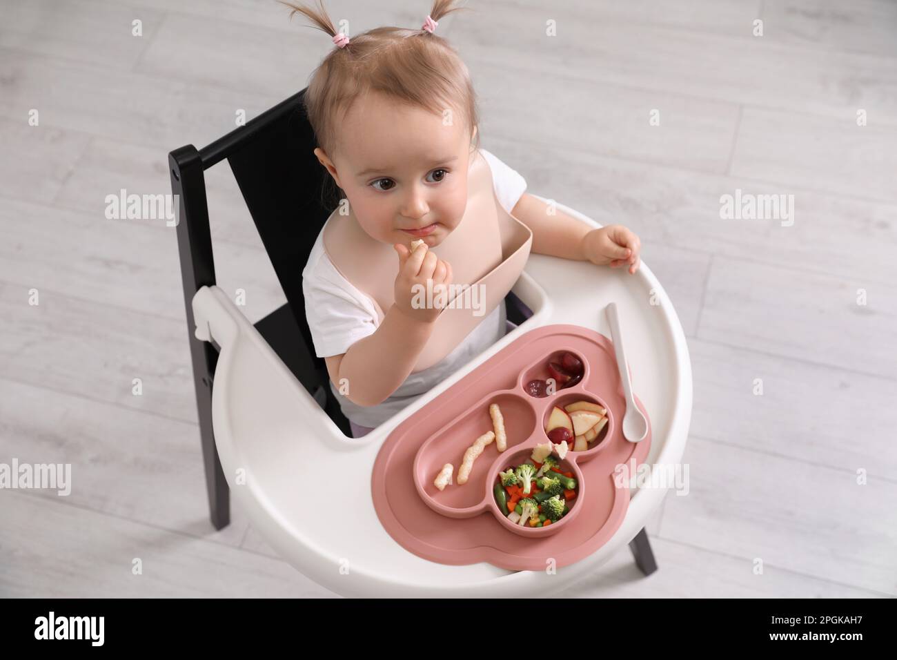 Cute little baby eating food in high chair indoors, above view Stock ...