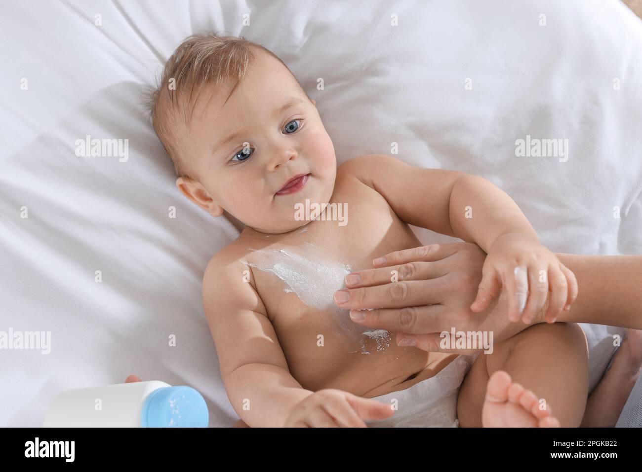 Mother applying dusting powder onto her baby on bed, top view Stock ...