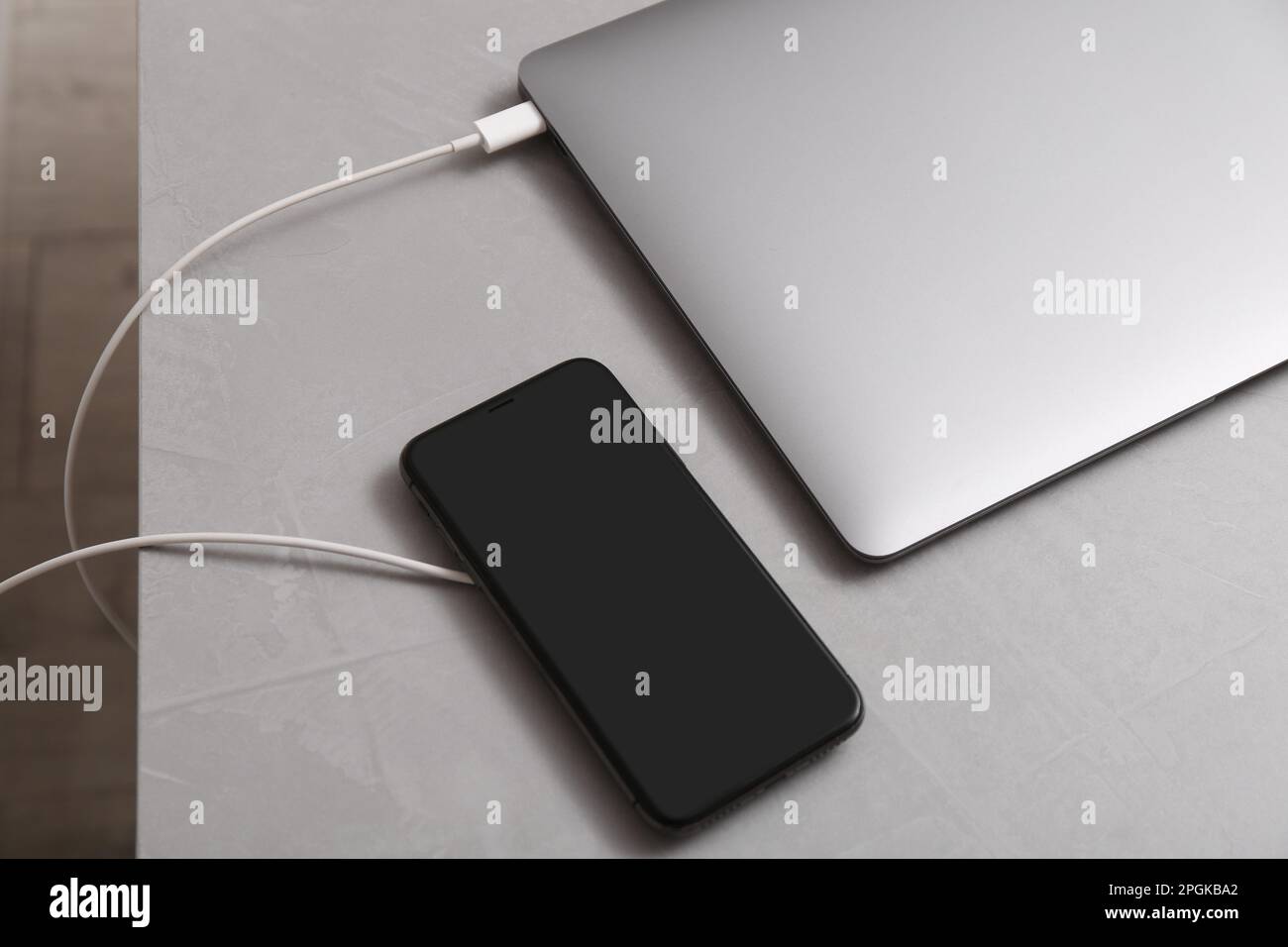 Smartphone with wireless charger connected to laptop on light grey ...