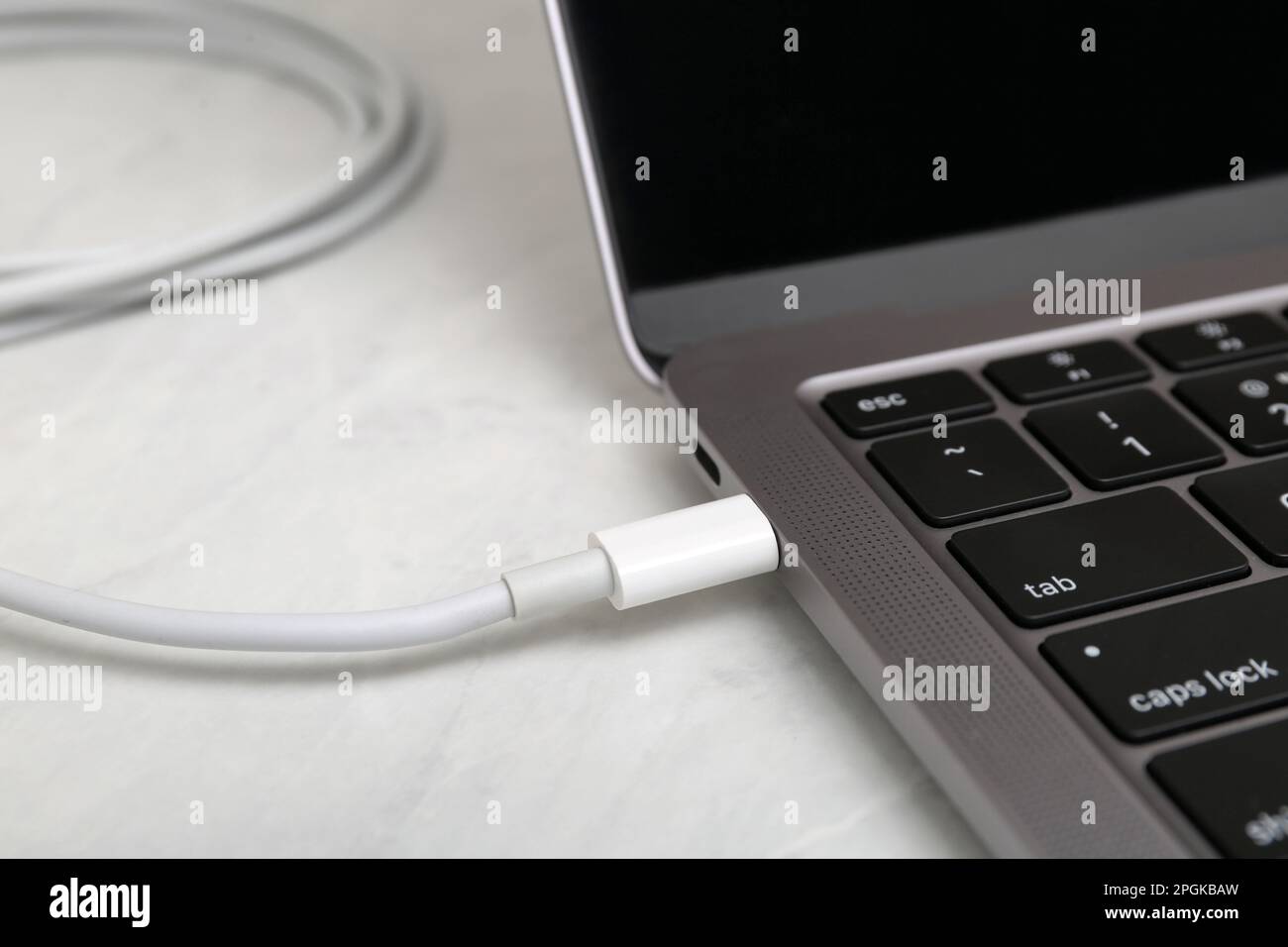 Charge cable connected to laptop on light table, closeup Stock Photo ...