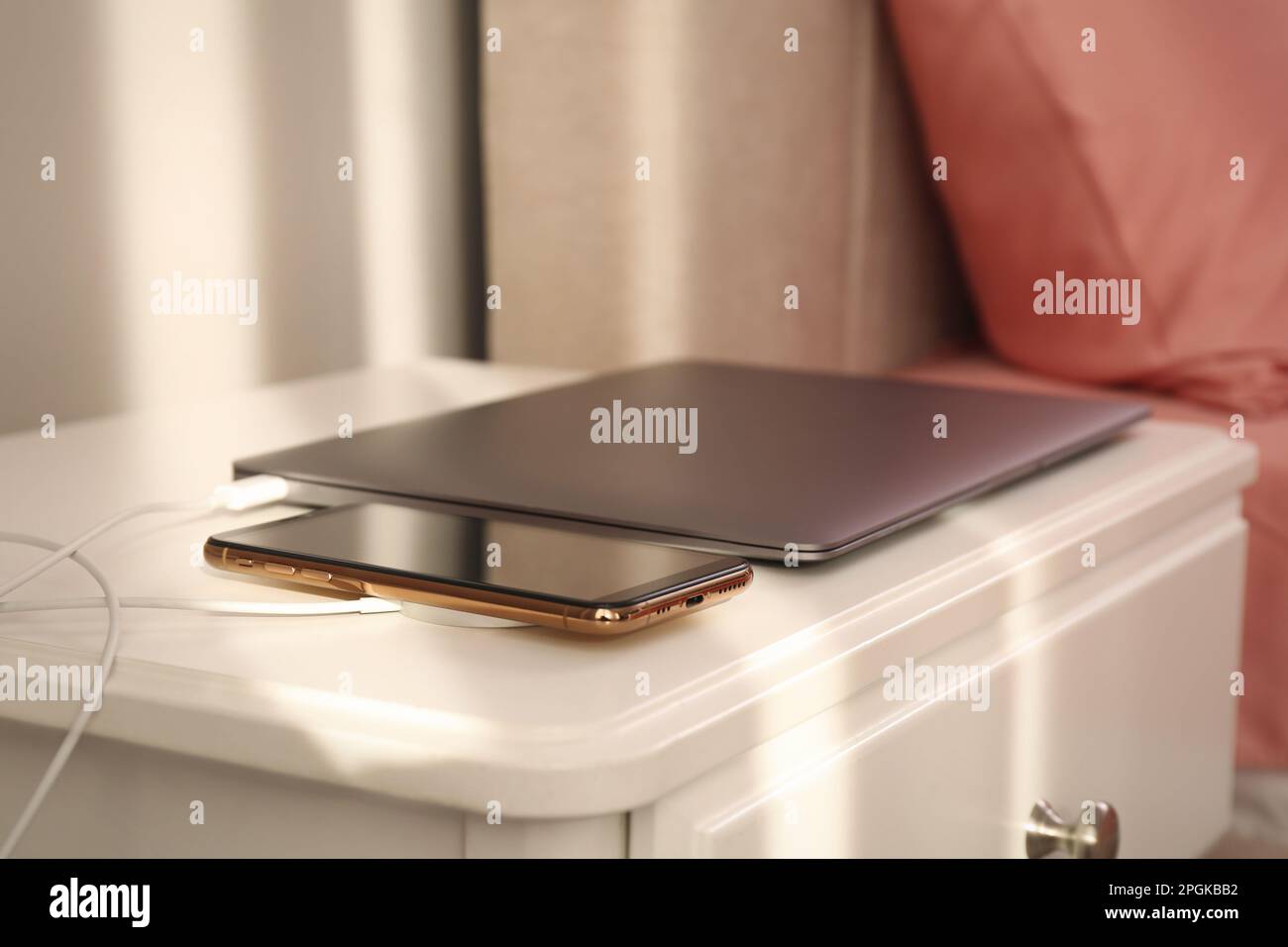 Smartphone with wireless charger connected to laptop on white table in ...