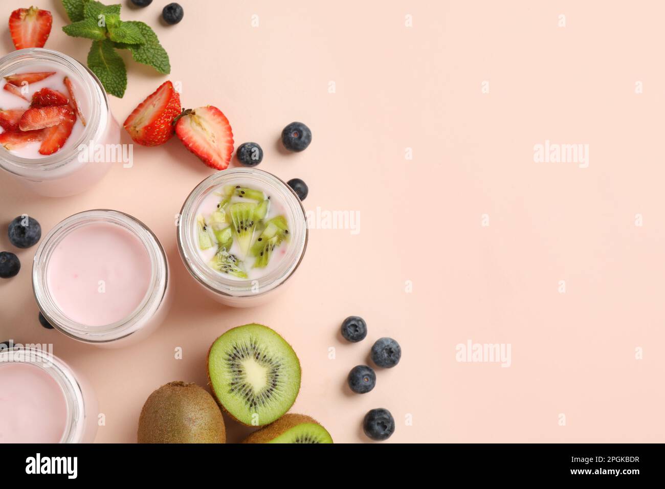 Jars of fresh yogurt and different fruits on light pink background ...