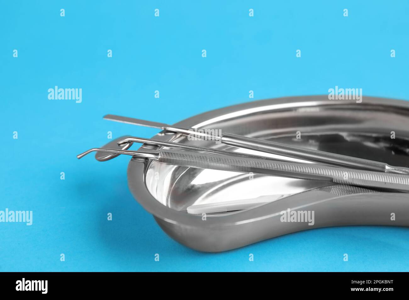 Kidney shaped tray with set of dentist's tools on light blue background ...