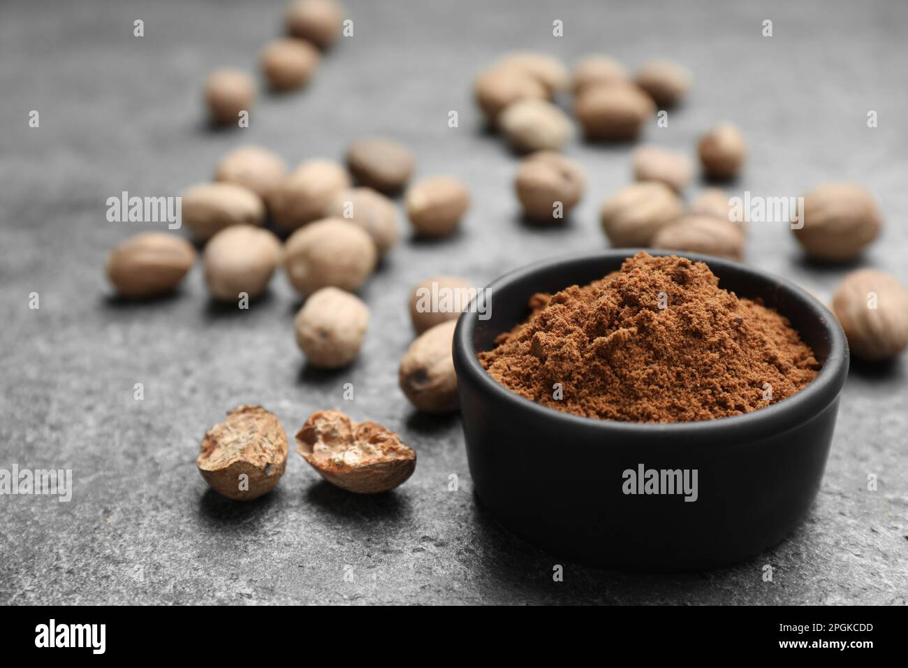 Bowl of nutmeg powder and seeds on grey table, space for text Stock ...