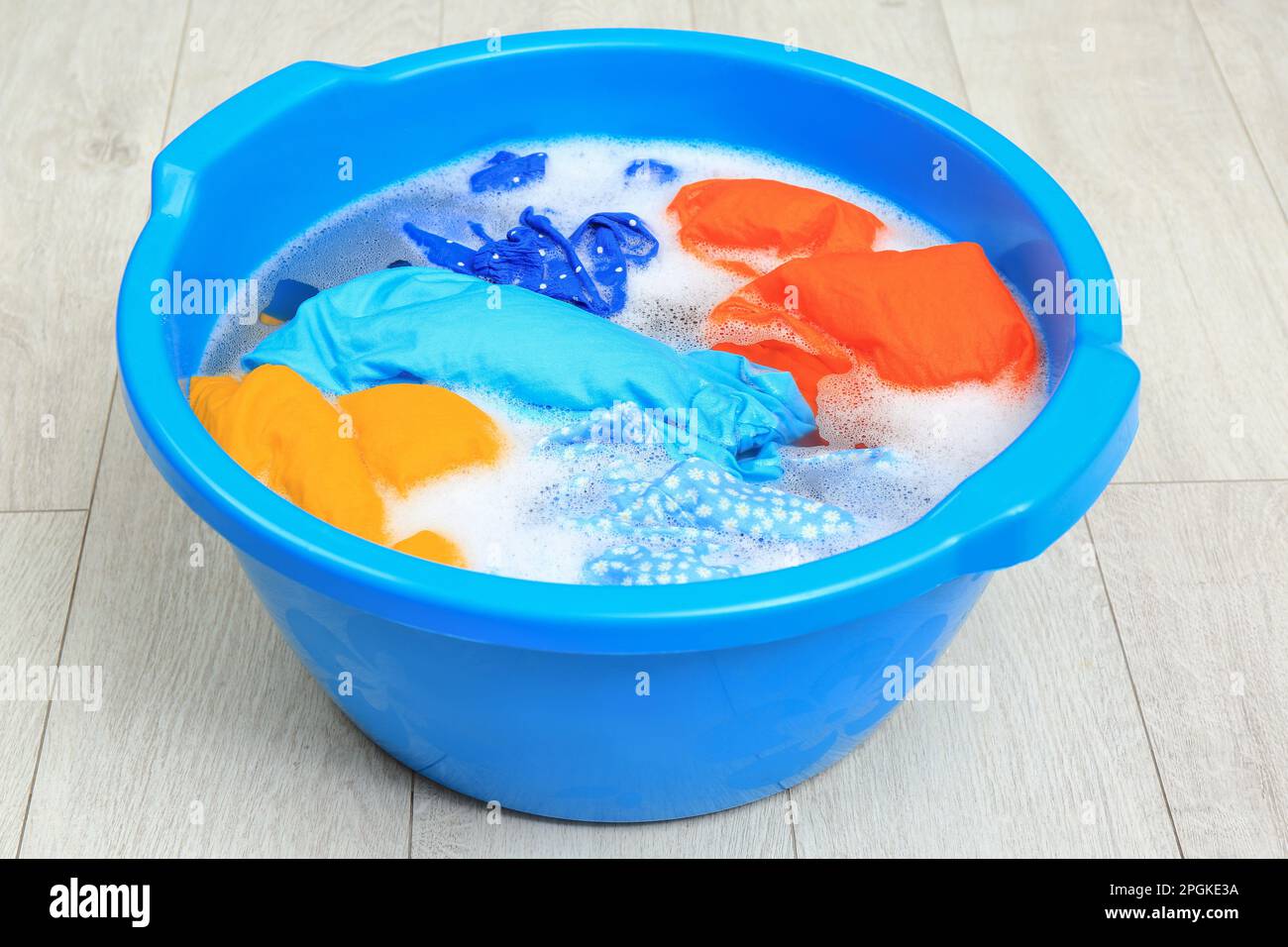Basin with colorful clothes on floor. Hand washing laundry Stock Photo ...