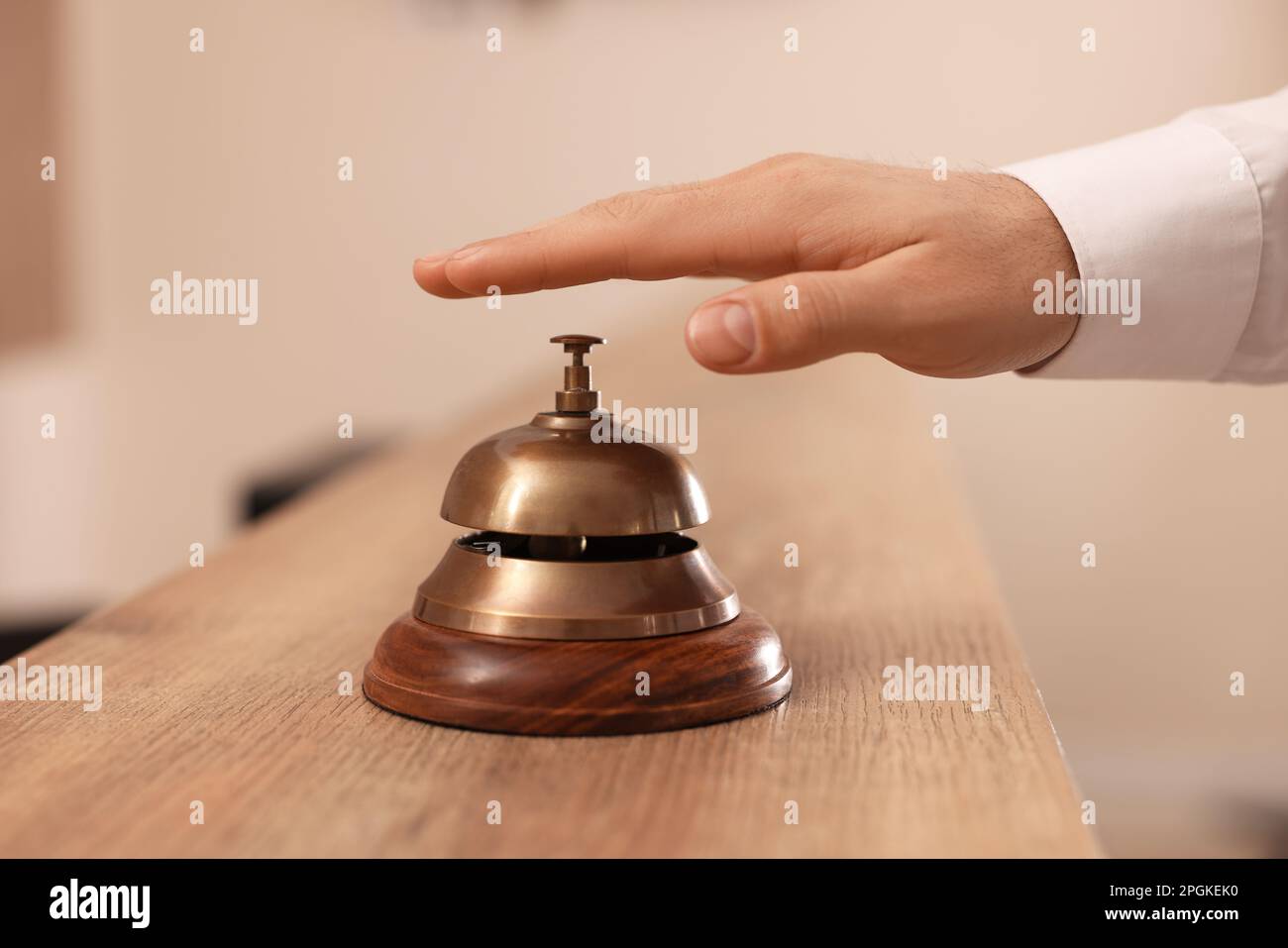 Man ringing service bell at wooden reception desk in hotel, closeup ...