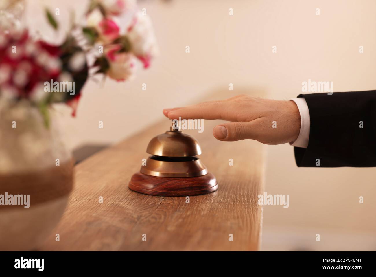 Man ringing service bell at wooden reception desk in hotel, closeup ...