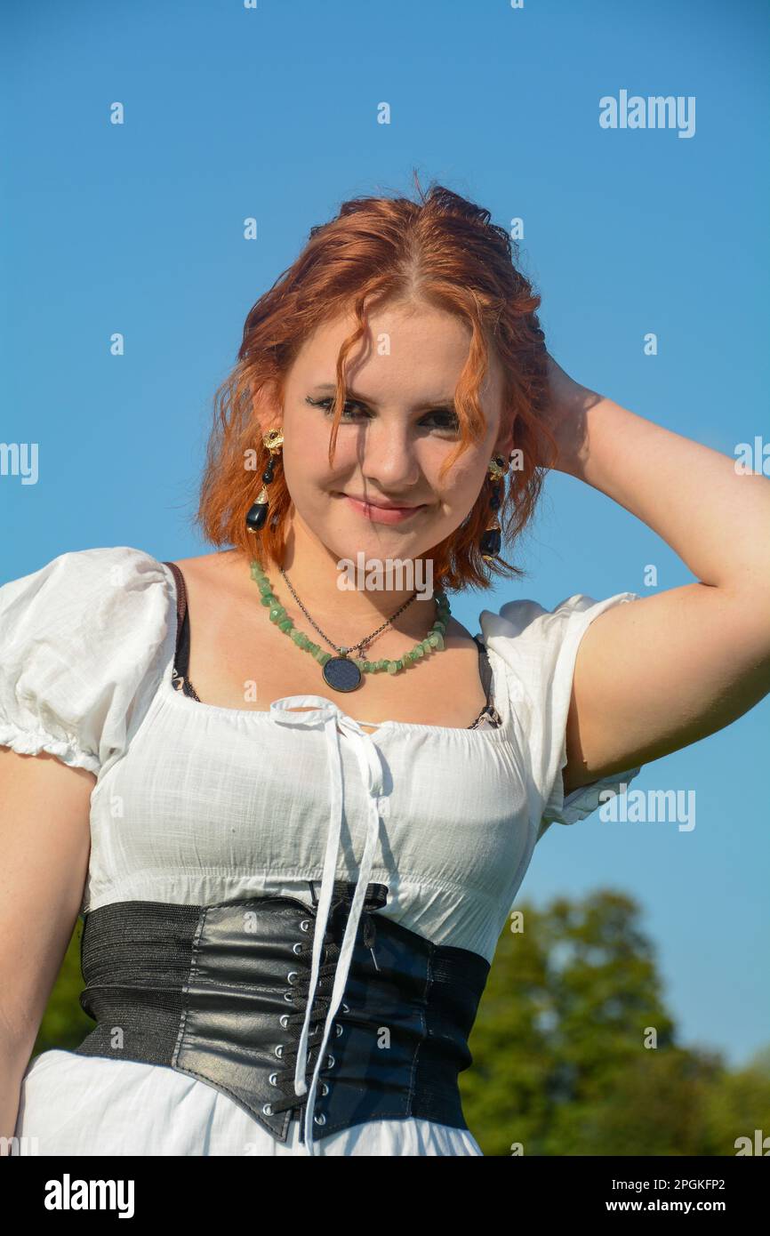 Portrait of a pretty young woman wearing white top, standing outdoors ...