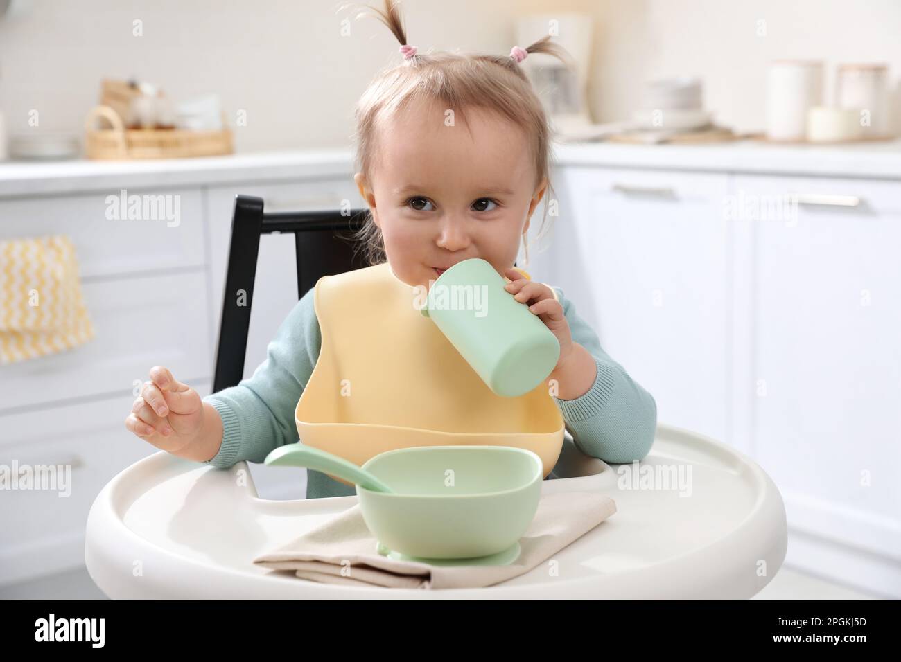Cute little baby drinking from bottle in kitchen Stock Photo - Alamy