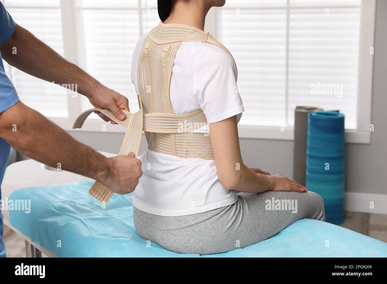Orthopedist helping patient to put on posture corrector in clinic ...