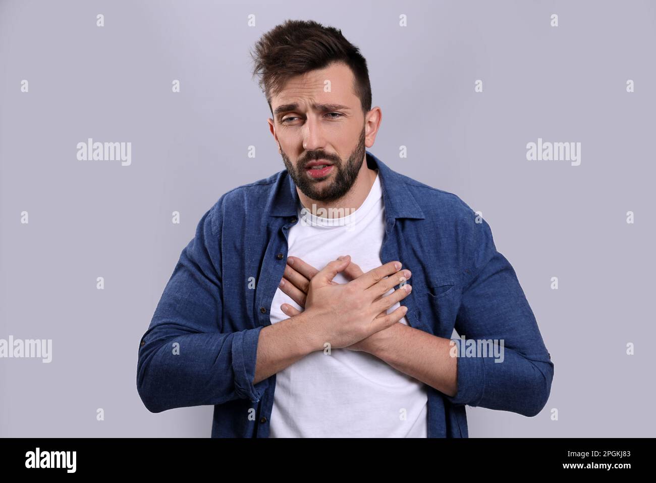 Man suffering from cold on grey background Stock Photo - Alamy