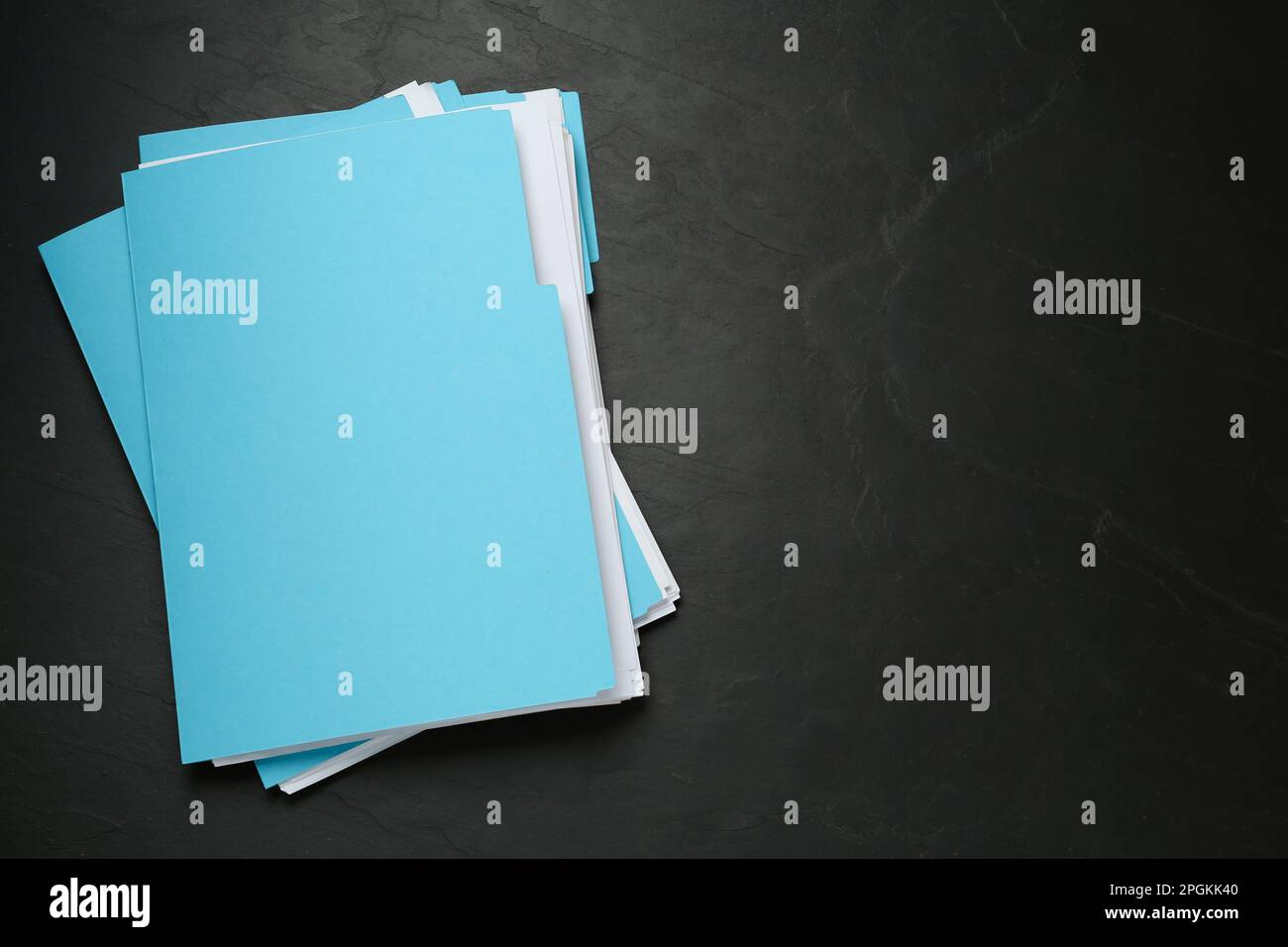 Turquoise files with documents on black slate table, top view. Space ...