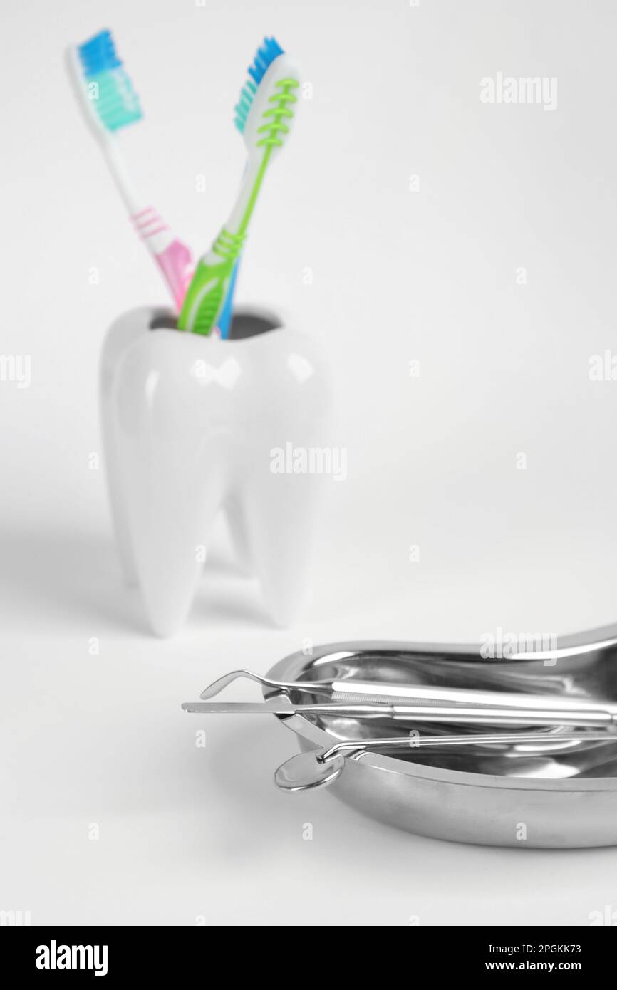 Kidney shaped tray with set of dentist's tools on light background ...