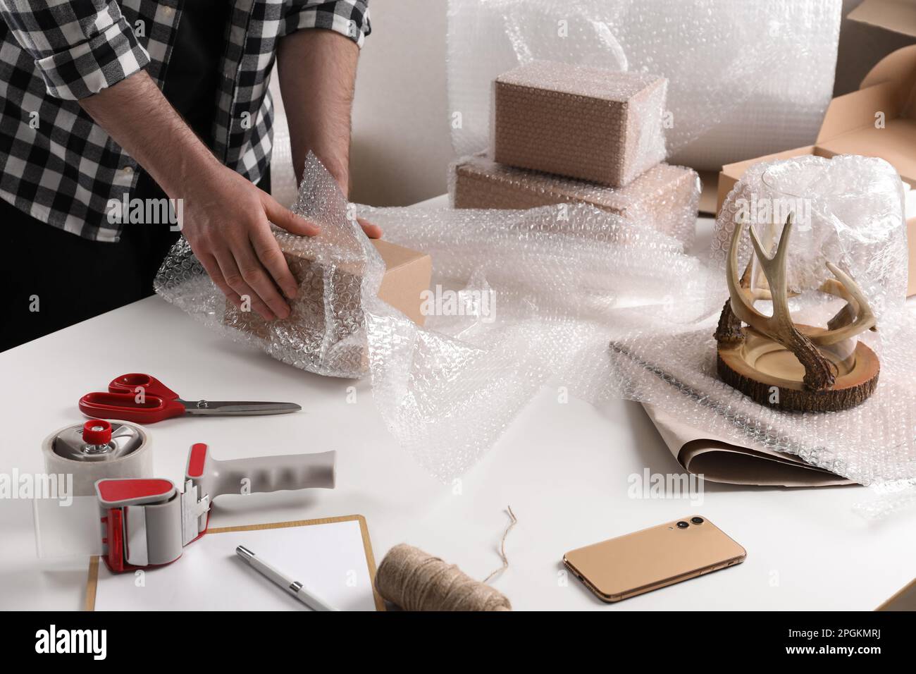 Man covering box with bubble wrap at table in warehouse, closeup Stock ...