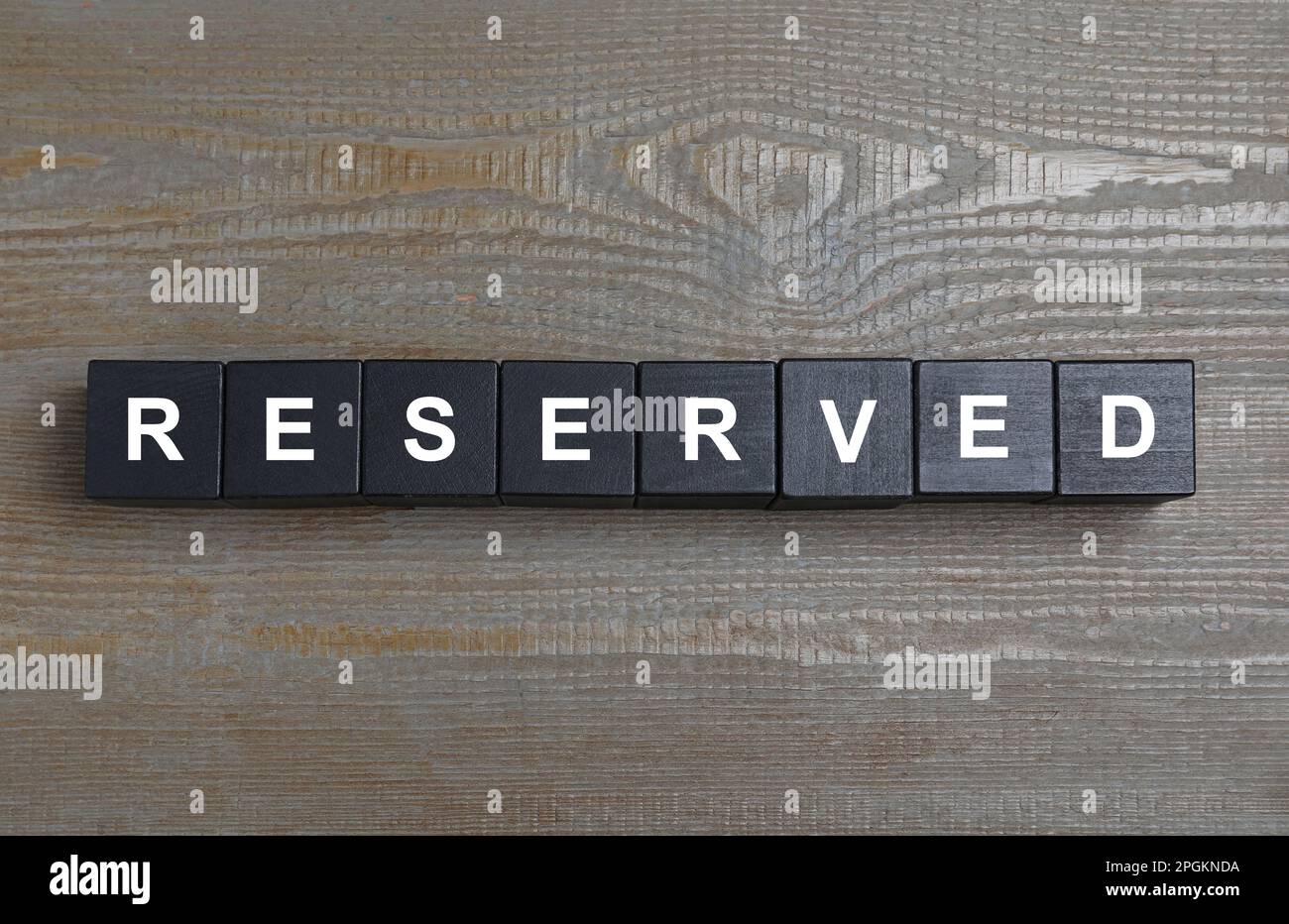 Word RESERVED made with cubes on wooden surface, top view. Table ...