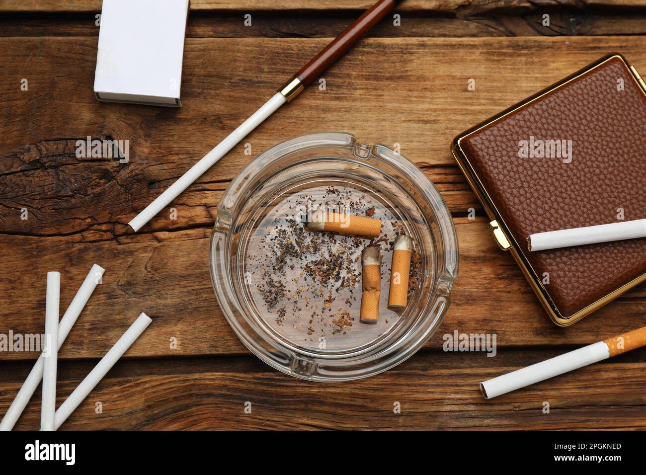 Cigarettes, case, holder, matchbox and ashtray with stubs on wooden ...