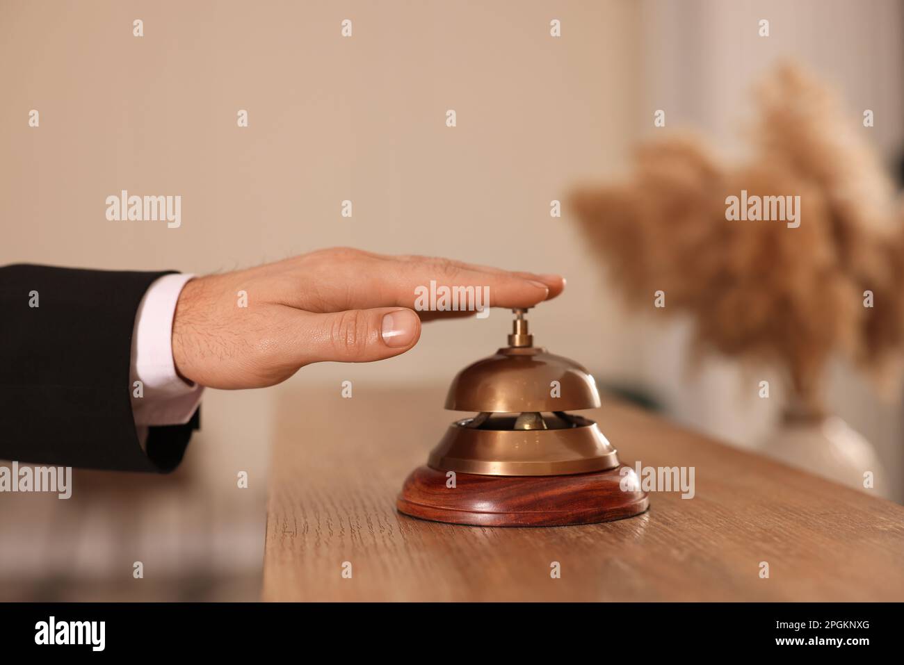 Man ringing service bell at wooden reception desk in hotel, closeup ...