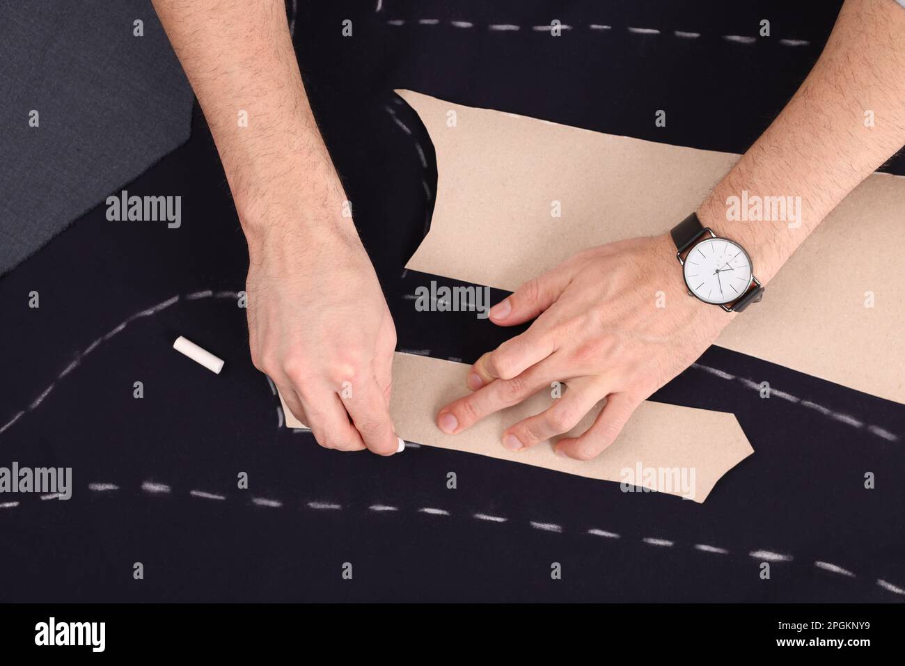 Tailor marking sewing pattern on fabric with chalk at table, top view ...