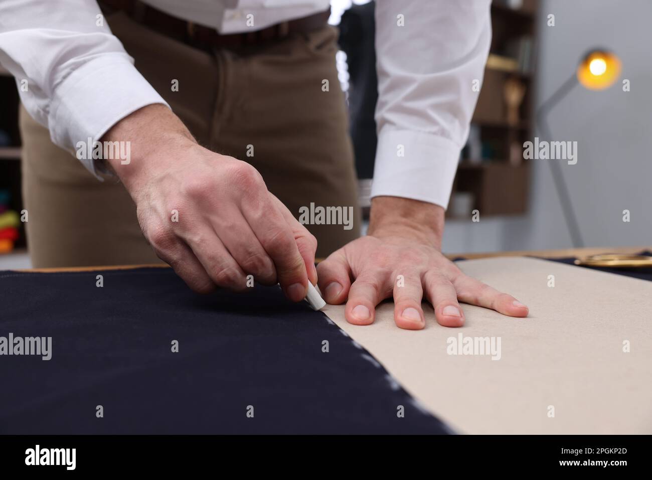 Tailor marking sewing pattern on fabric with chalk at table, closeup ...