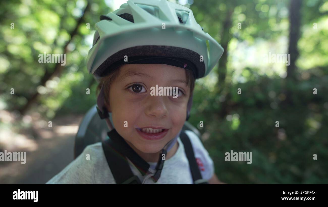 Happy child wearing bicycle helmet outdoors in forest park. Little boy ...